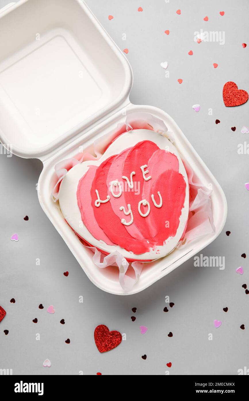 Plastic lunch box with heart-shaped bento cake on grey background ...