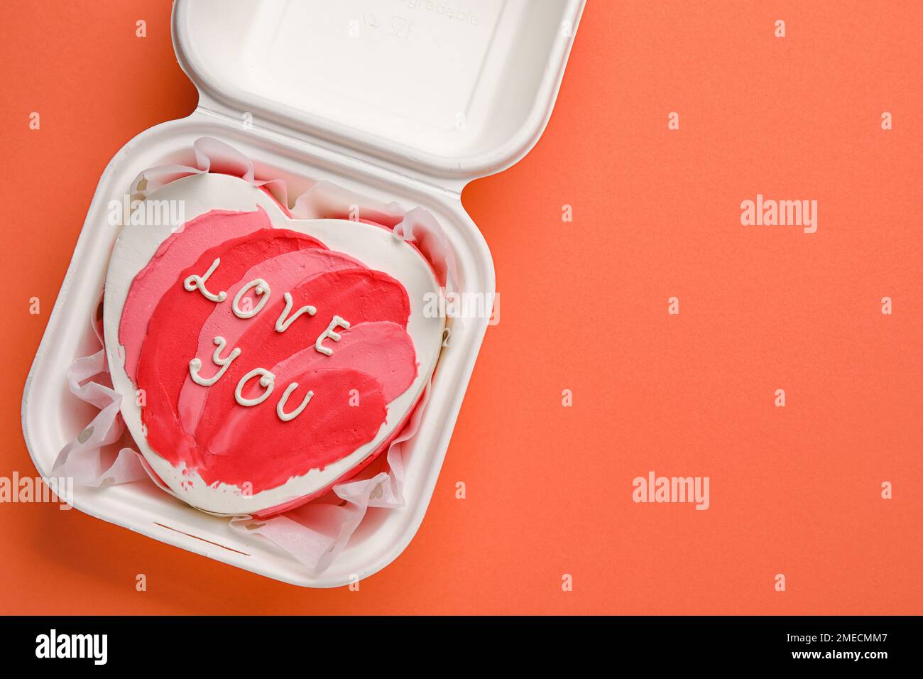 Plastic lunch box with heart-shaped bento cake on orange background ...