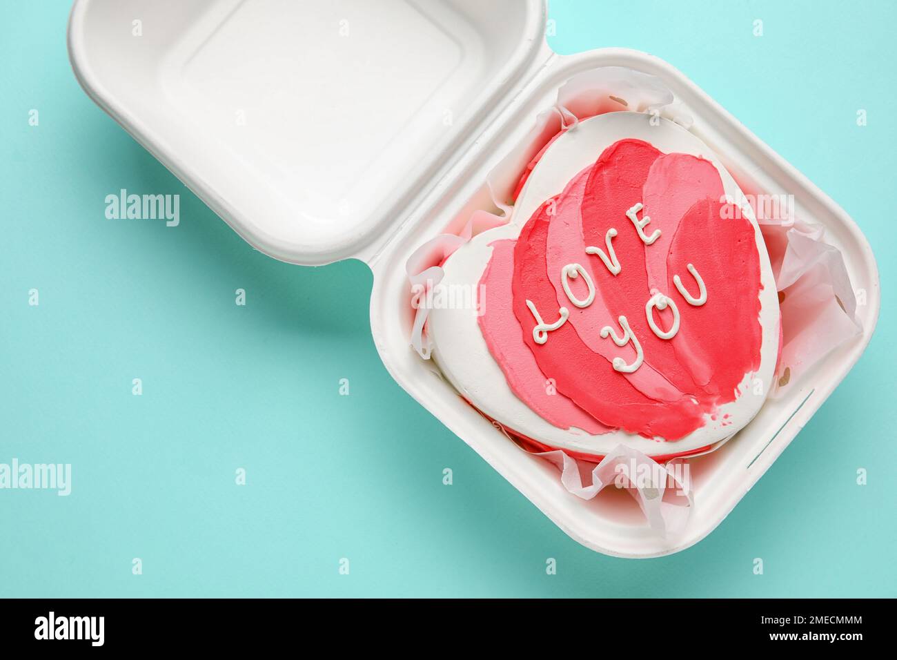 Plastic lunch box with heart-shaped bento cake on turquoise background ...