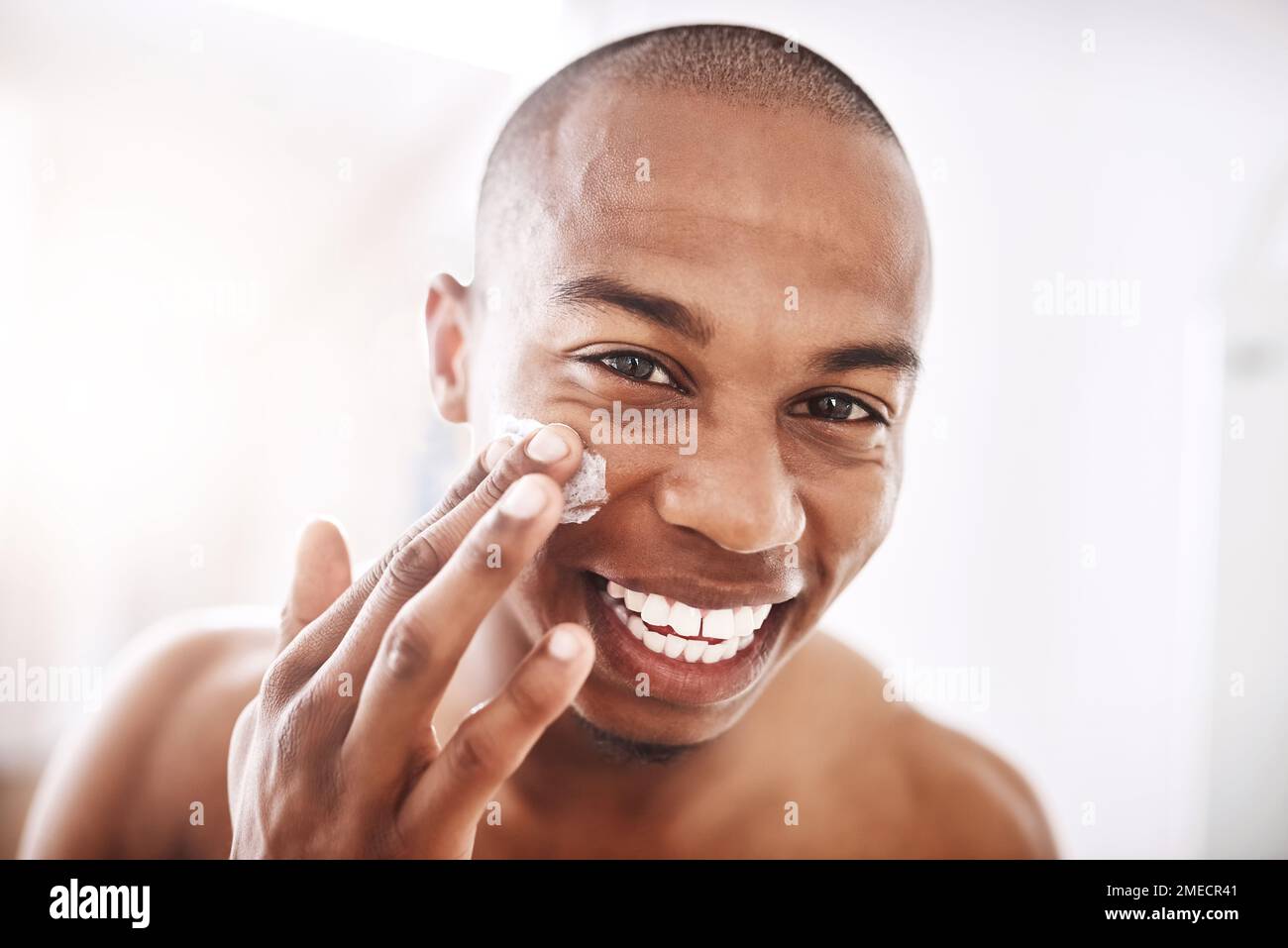 My skin is healthy and popping. Portrait of a handsome young man applying moisturizer to his ...