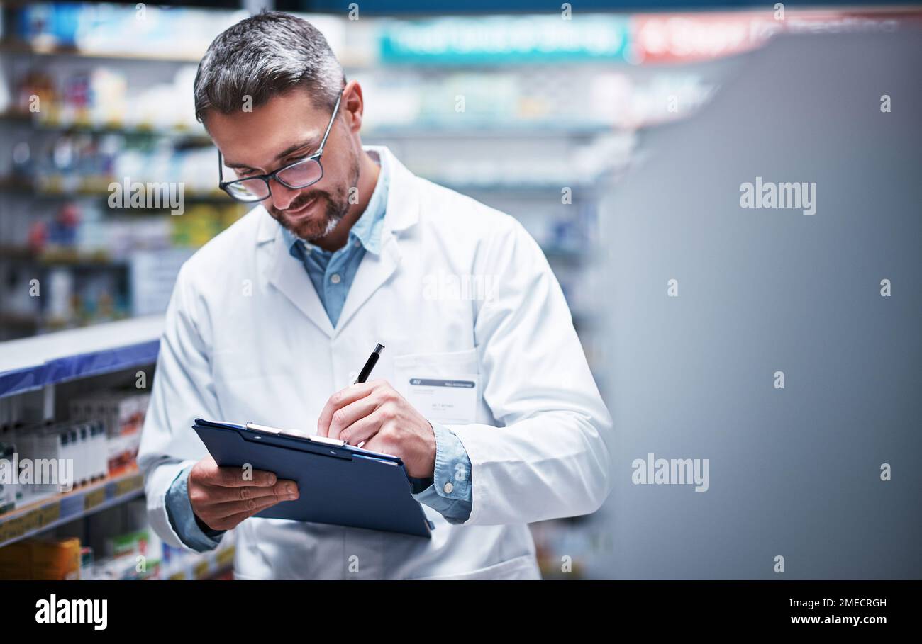 Recording notes about all the inventory. a mature pharmacist writing on ...