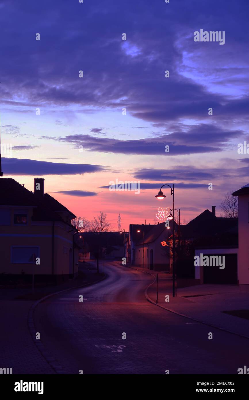 A village road with traditional houses and lamp posts with sunset ...