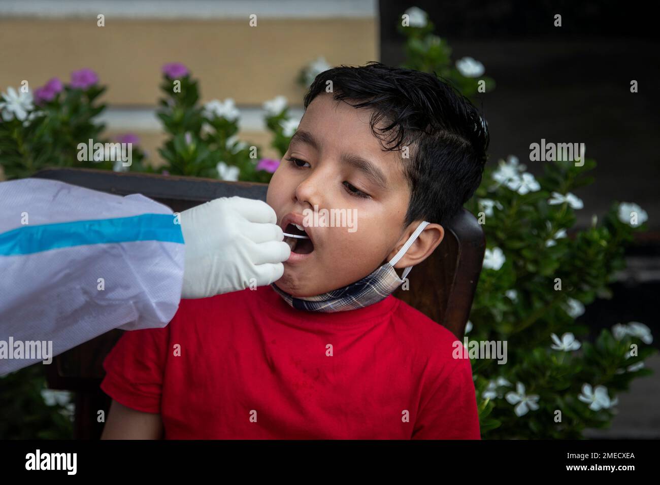 A health worker takes a nasal swab sample of a child to test for COVID ...
