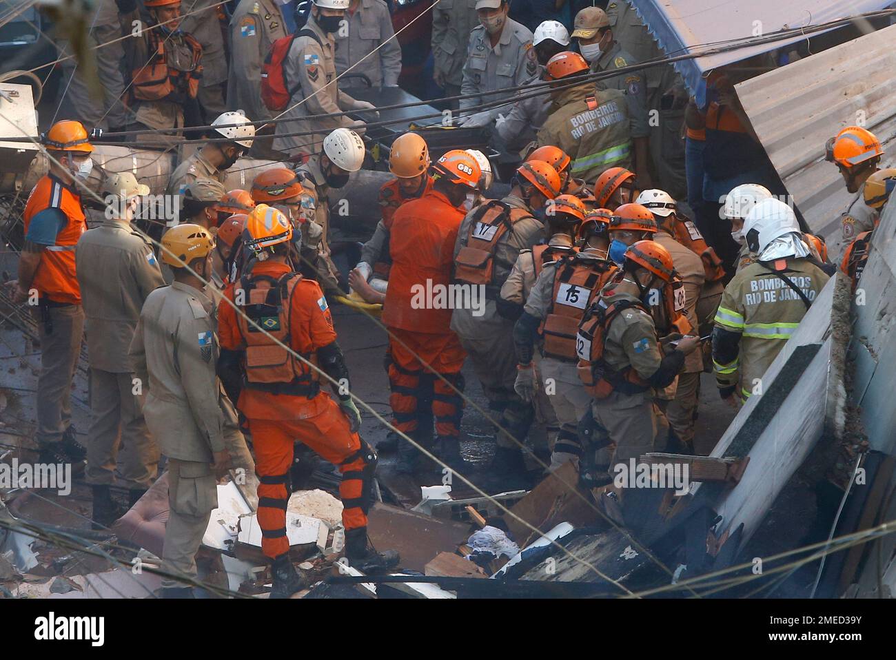 Firefighters pull a person from the debris of a four-floor building ...