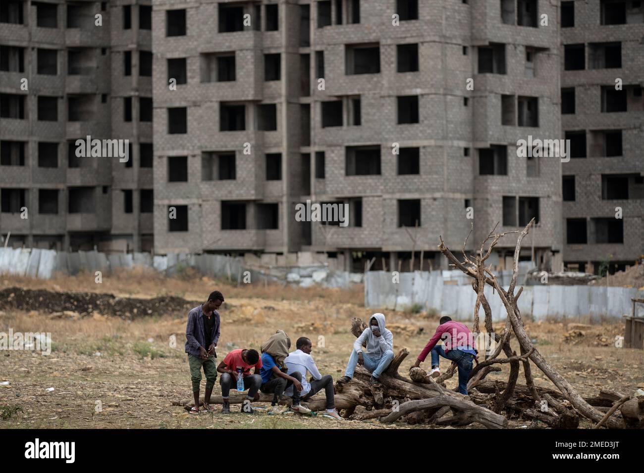 Displaced Tigrayans sit on pieces of wood on waste ground at a ...