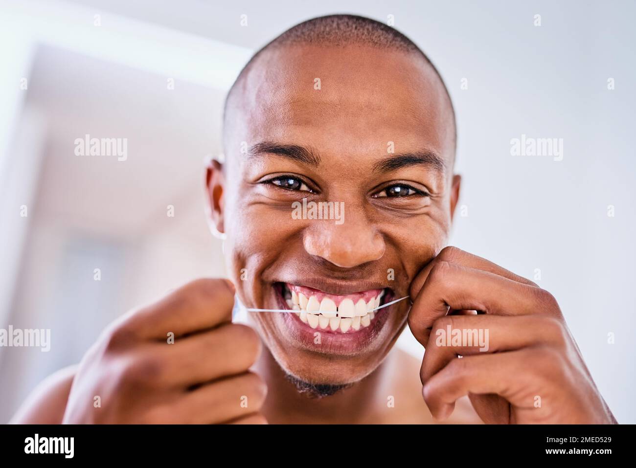 Healthy teeth, now thats something to smile about. an attractive young man flossing his teeth in ...