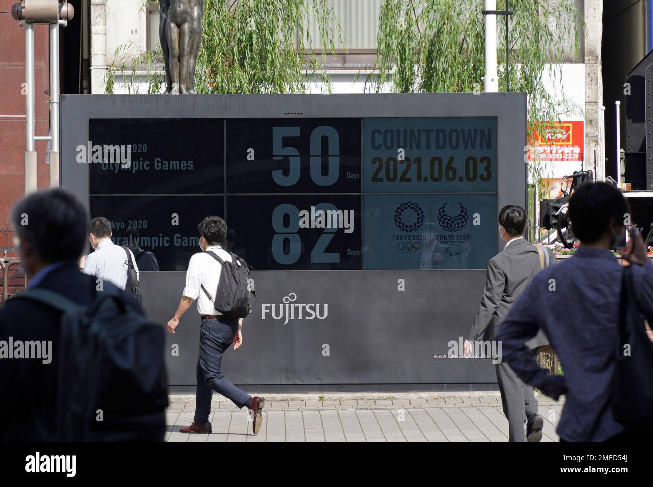 People walk by the countdown clock for the Tokyo 2020 Olympic and ...