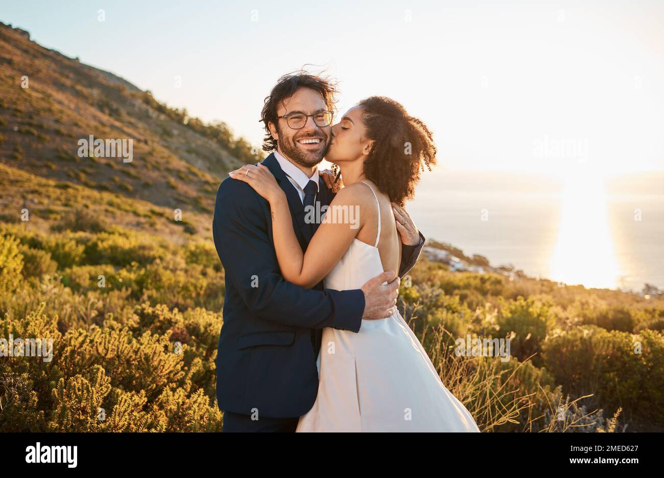 Married couple, kiss and cheek and smile in nature for honeymoon ...