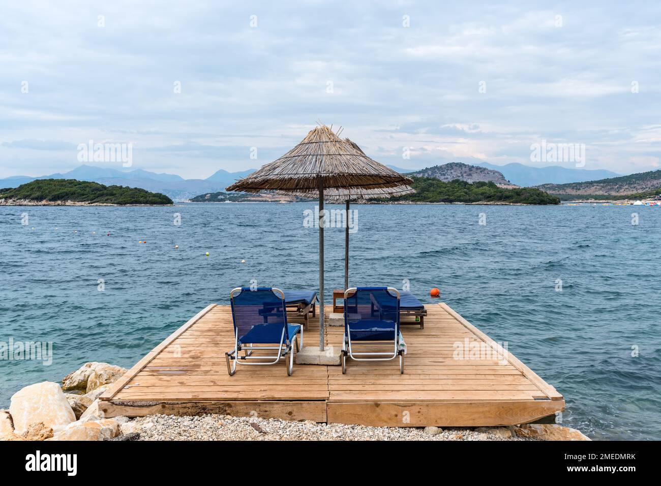 Four empty sun loungers under umbrellas on the seashore in cloudy ...