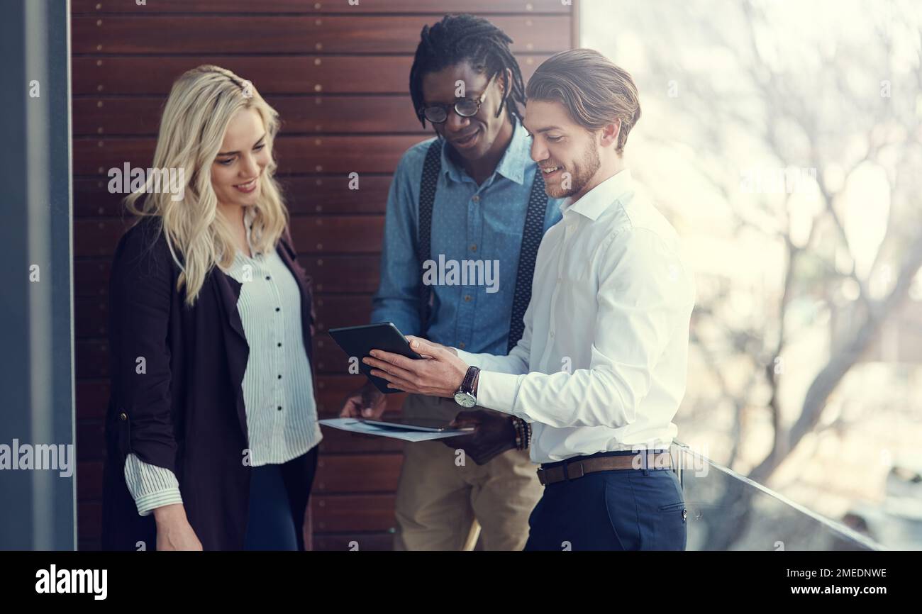 Getting their input. three young businesspeople using a tablet while ...