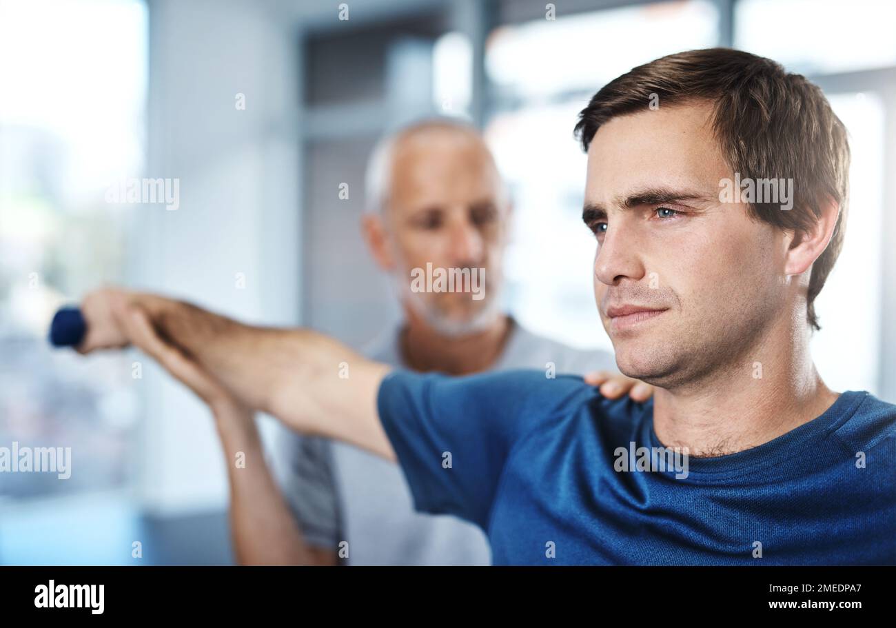 Determined to get through the pain. a physiotherapist helping a patient ...