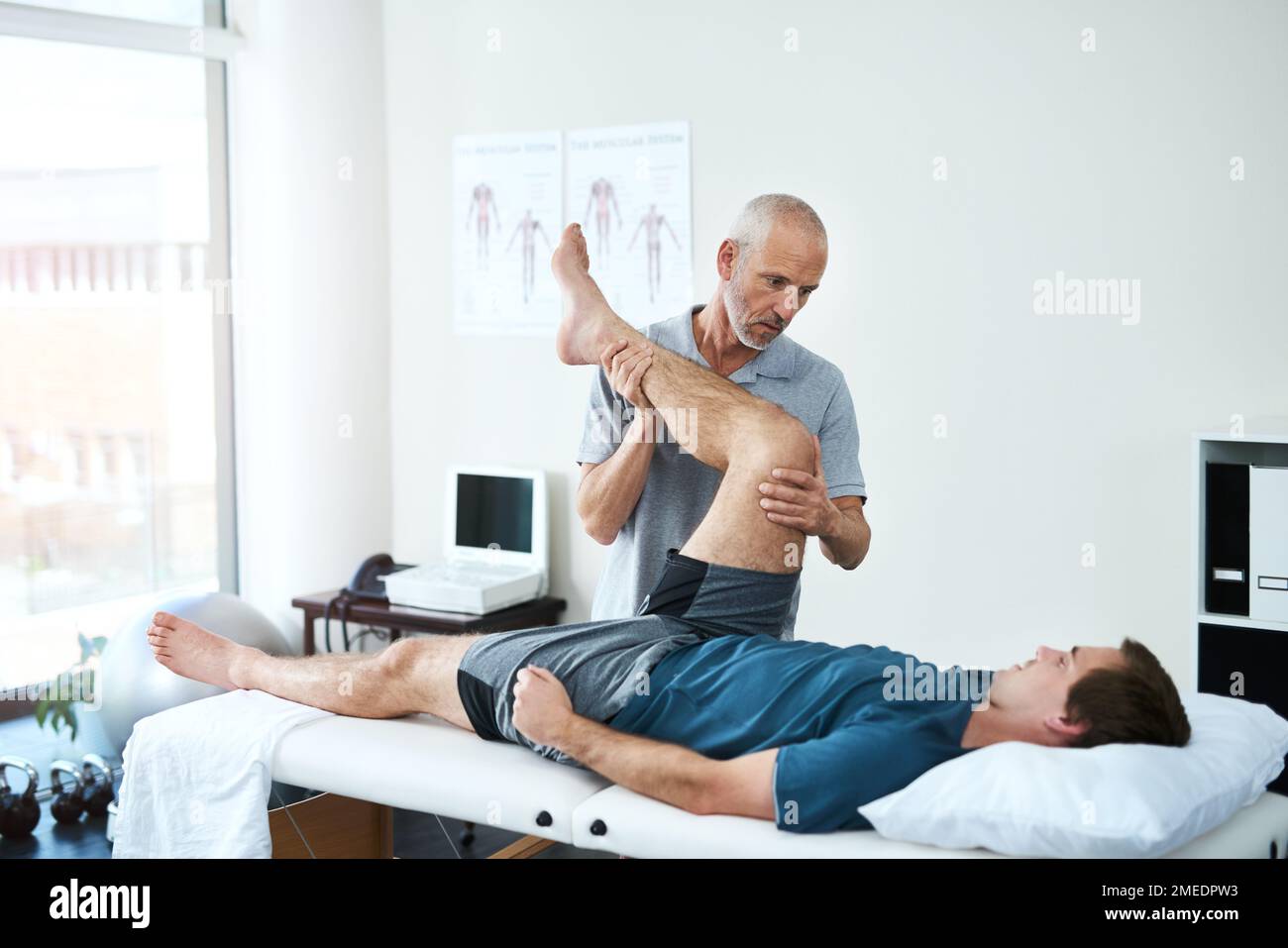 How does it feel now. a handsome mature male physiotherapist treating a ...