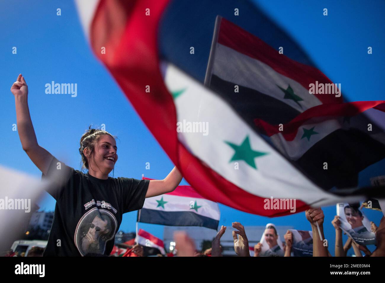 Syrian President Bashar Assad supporters hold up national flags and ...