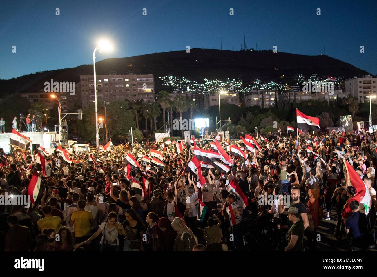 Syrian President Bashar Assad supporters hold up national flags and ...