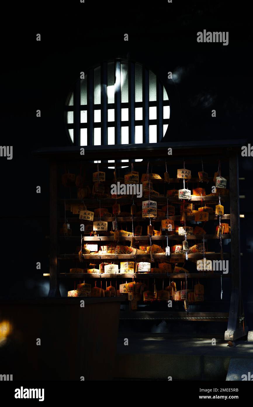 A vertical shot of light shining on the traditional Japanese ema in a ...