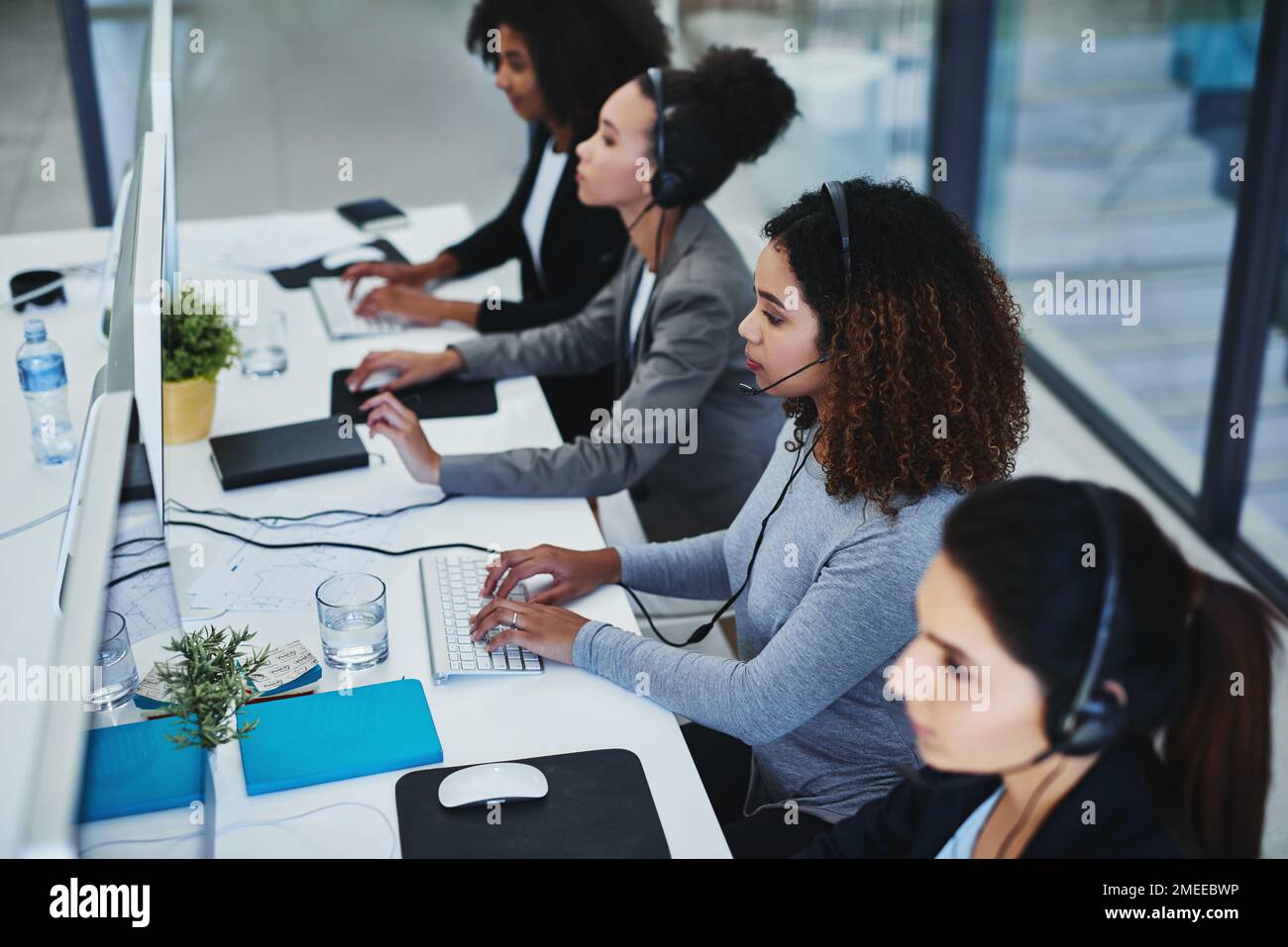 Working our way through enquiries. a diverse group of businesswomen wearing headsets and using ...