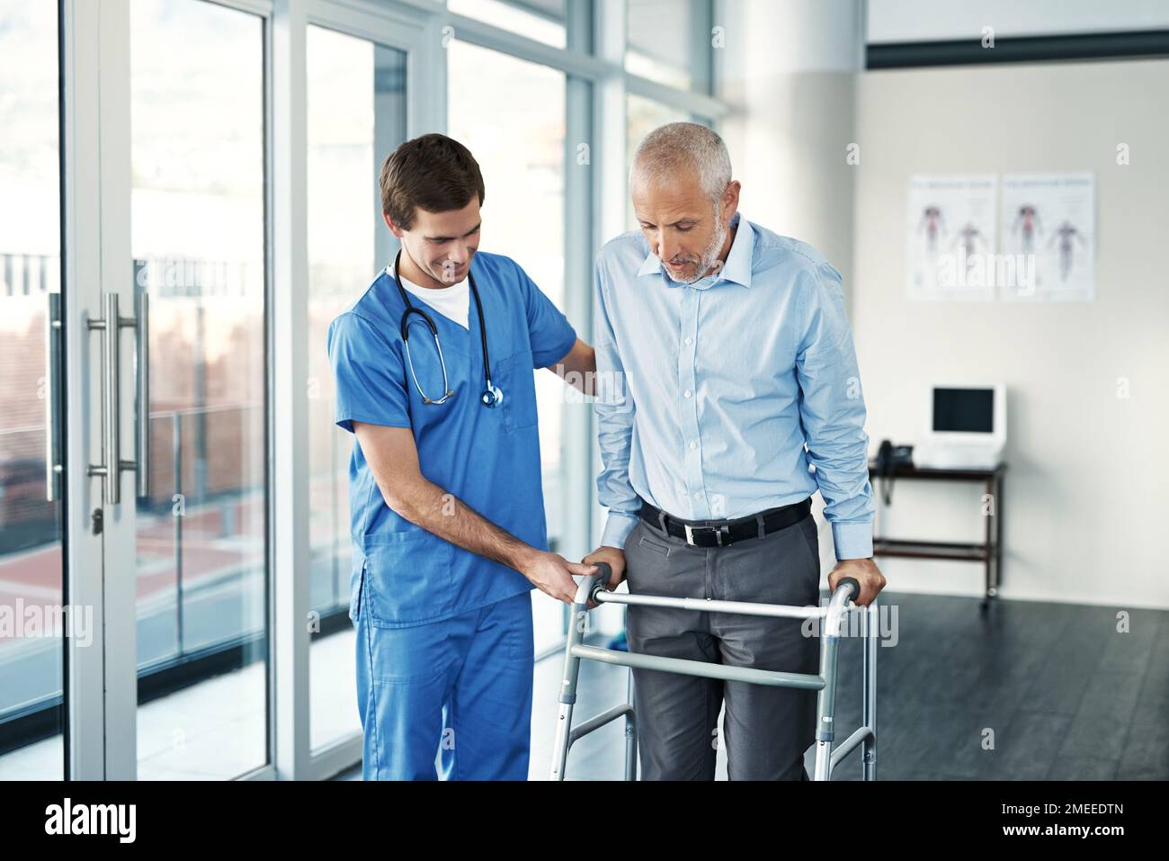 Slow and steady steps. a male nurse assisting a senior patient with a ...