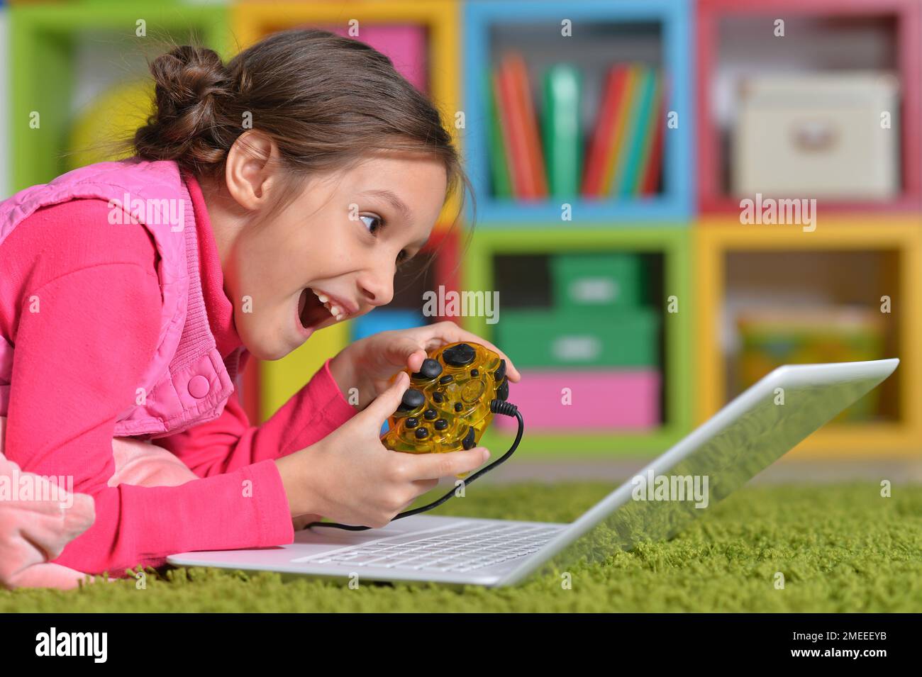 Cute little girl playing computer game with modern laptop Stock Photo ...