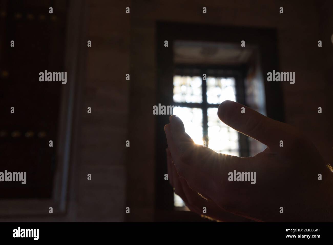 Muslim man praying or dua with raising hands in a mosque with sunlight ...