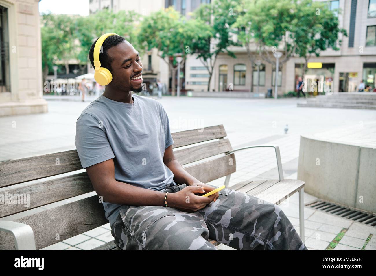 Man smiling while listening music with mobile phone and headphones ...