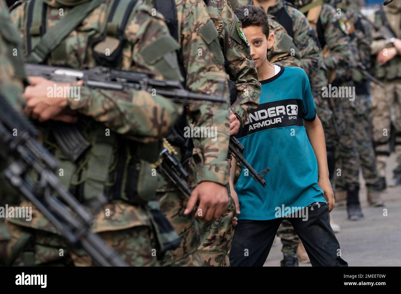 A child weaves between columns of Hamas militants as they parade ...