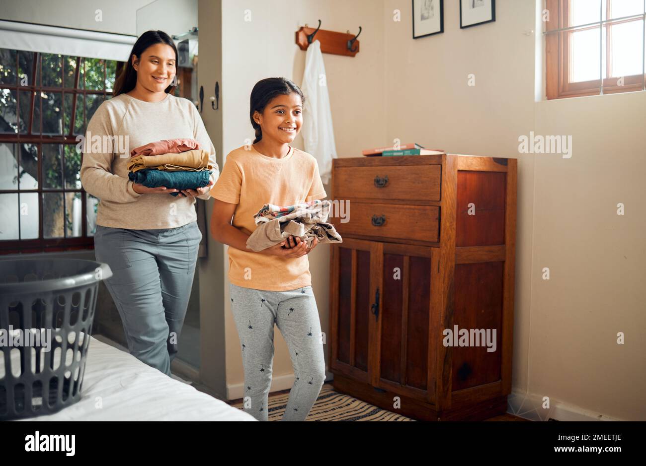 Cleaning, child and mother doing laundry clothes, house work and fold clean fabric, cotton or ...