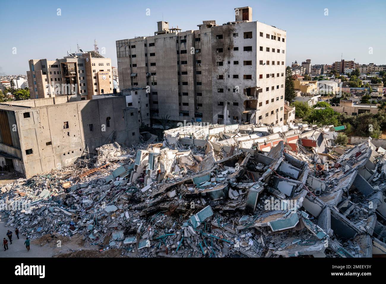 People walk past view rubble of the al-Jalaa building destroyed in a ...