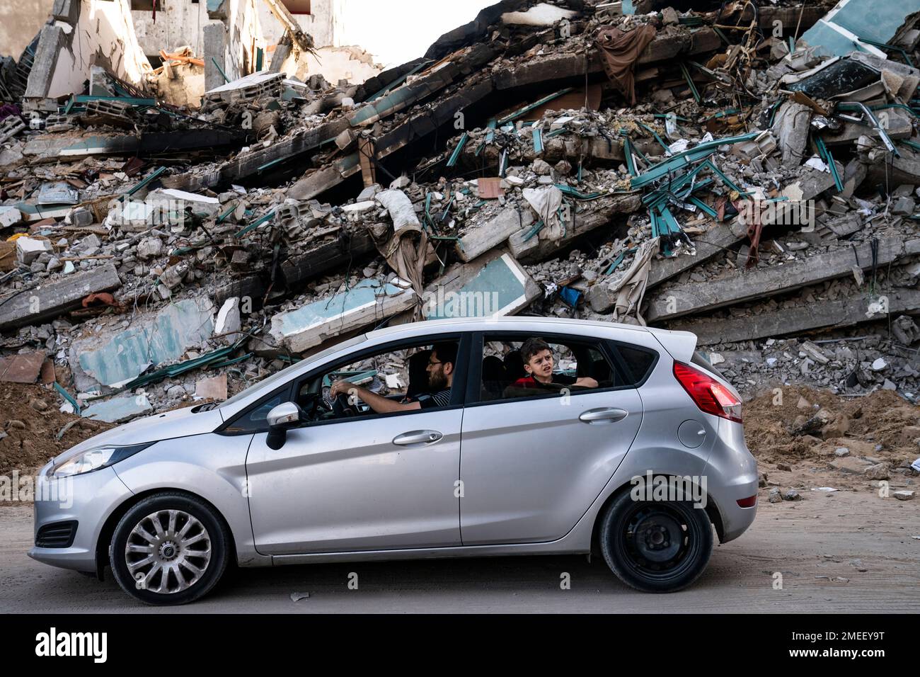People drive by the rubble of the al-Jalaa building following a cease ...