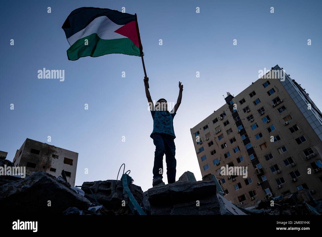A child raises a Palestinian flag and cheers as spectators gather ...