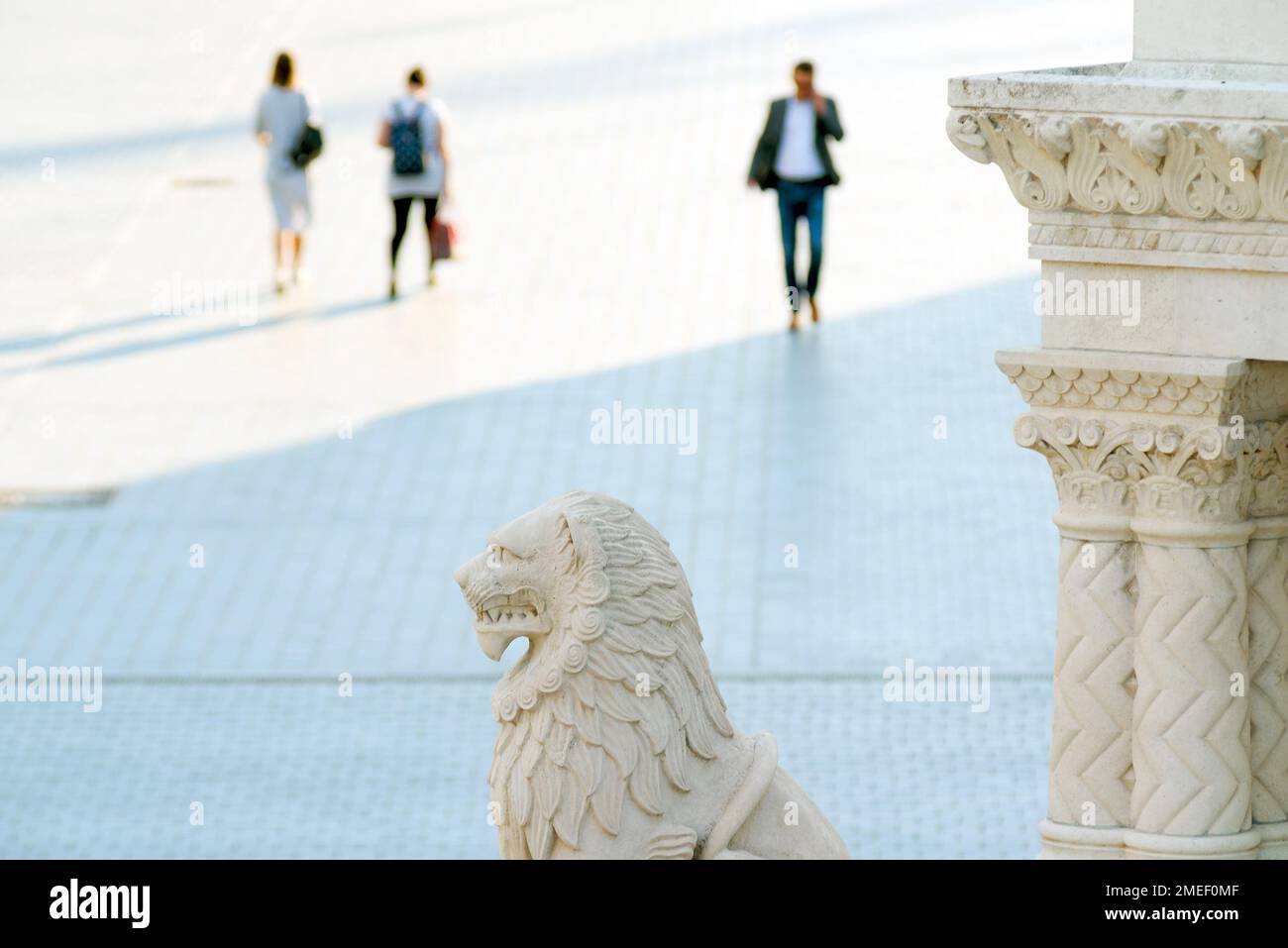 Defocused people walking against stone curved monument in the city ...