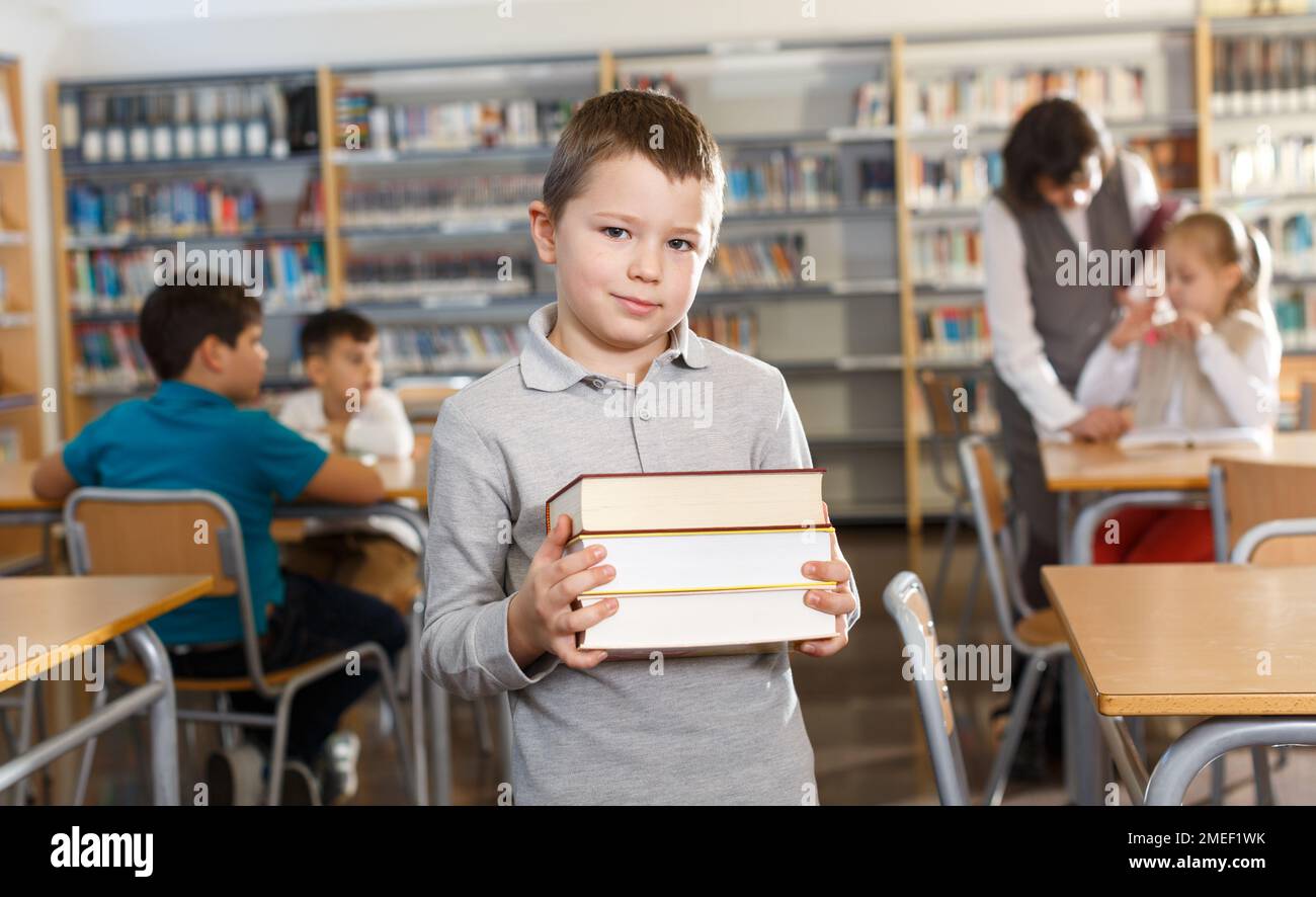 Smiling boy standing with pile of books Stock Photo - Alamy