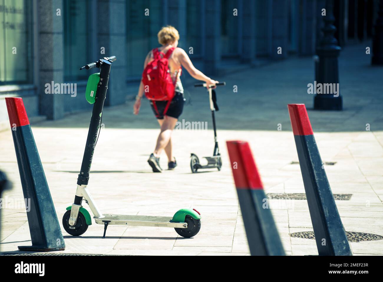 Shared scooter standing on the street against blurred person carrying a ...