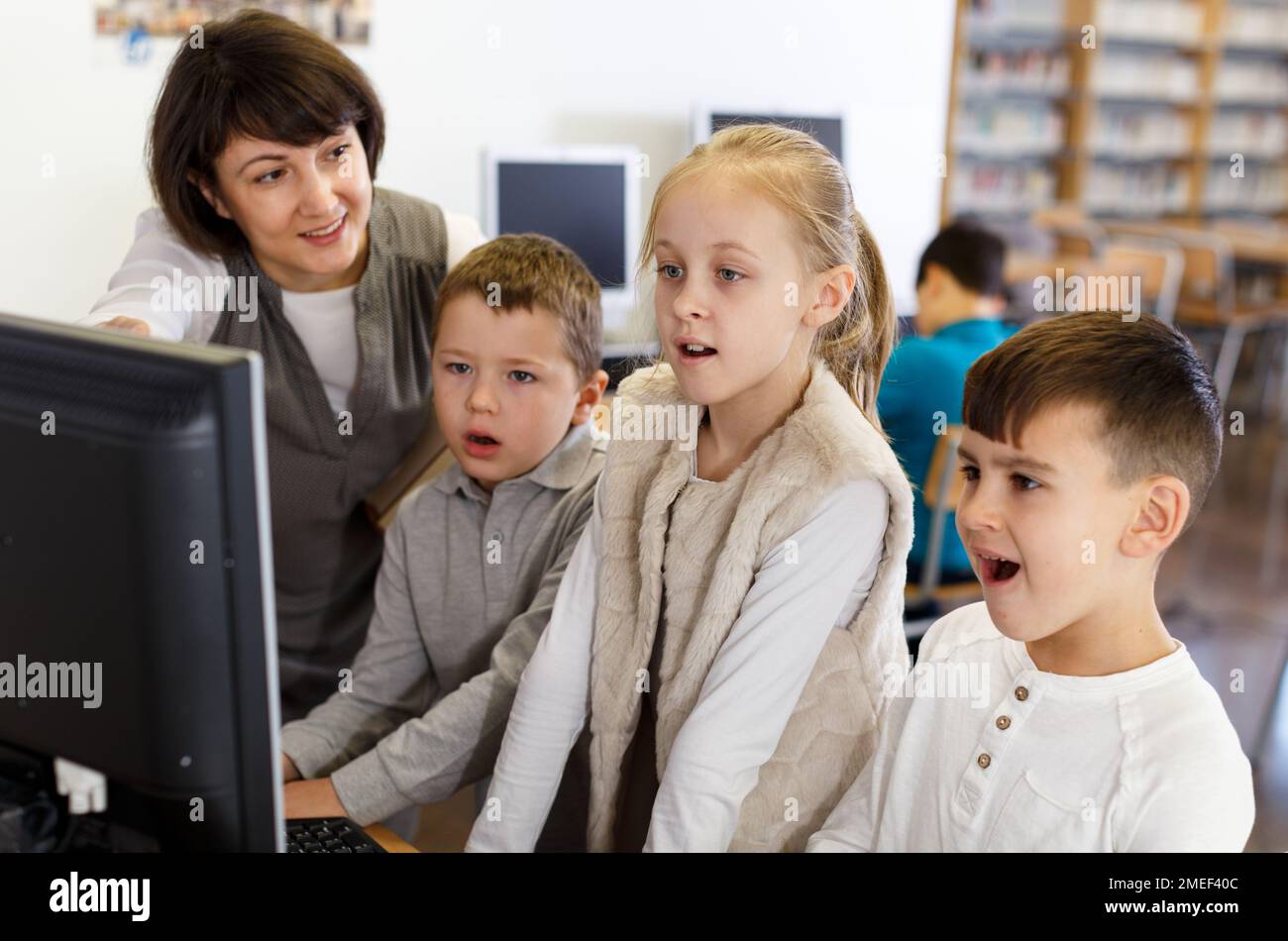 Female teacher giving lesson to kids in computer class Stock Photo - Alamy