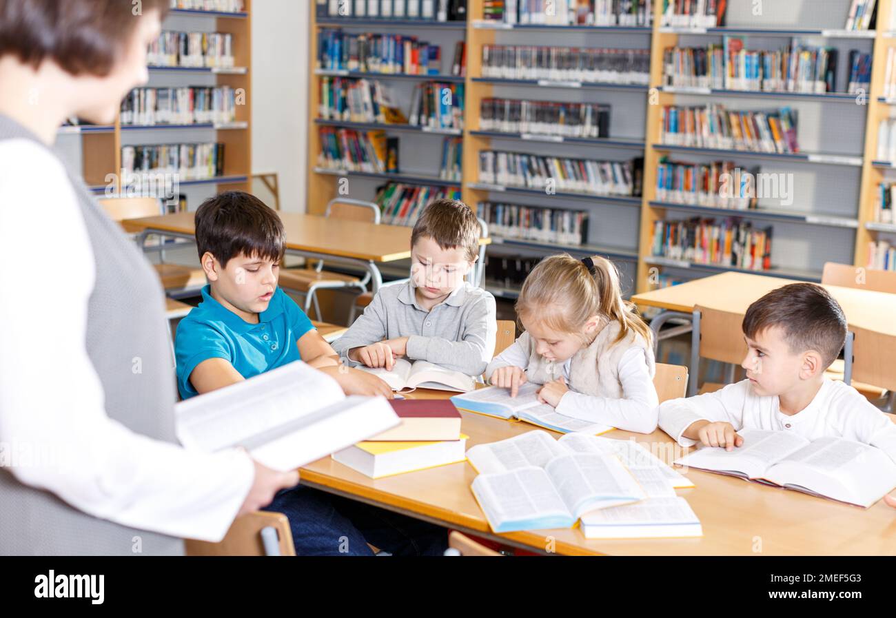 Female librarian and schoolkids during classes in library Stock Photo ...