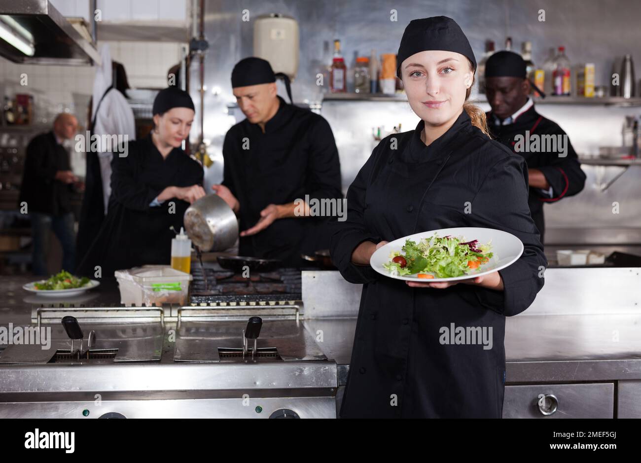 Confident female chef with a team of cooks in restaurant kitchen Stock ...