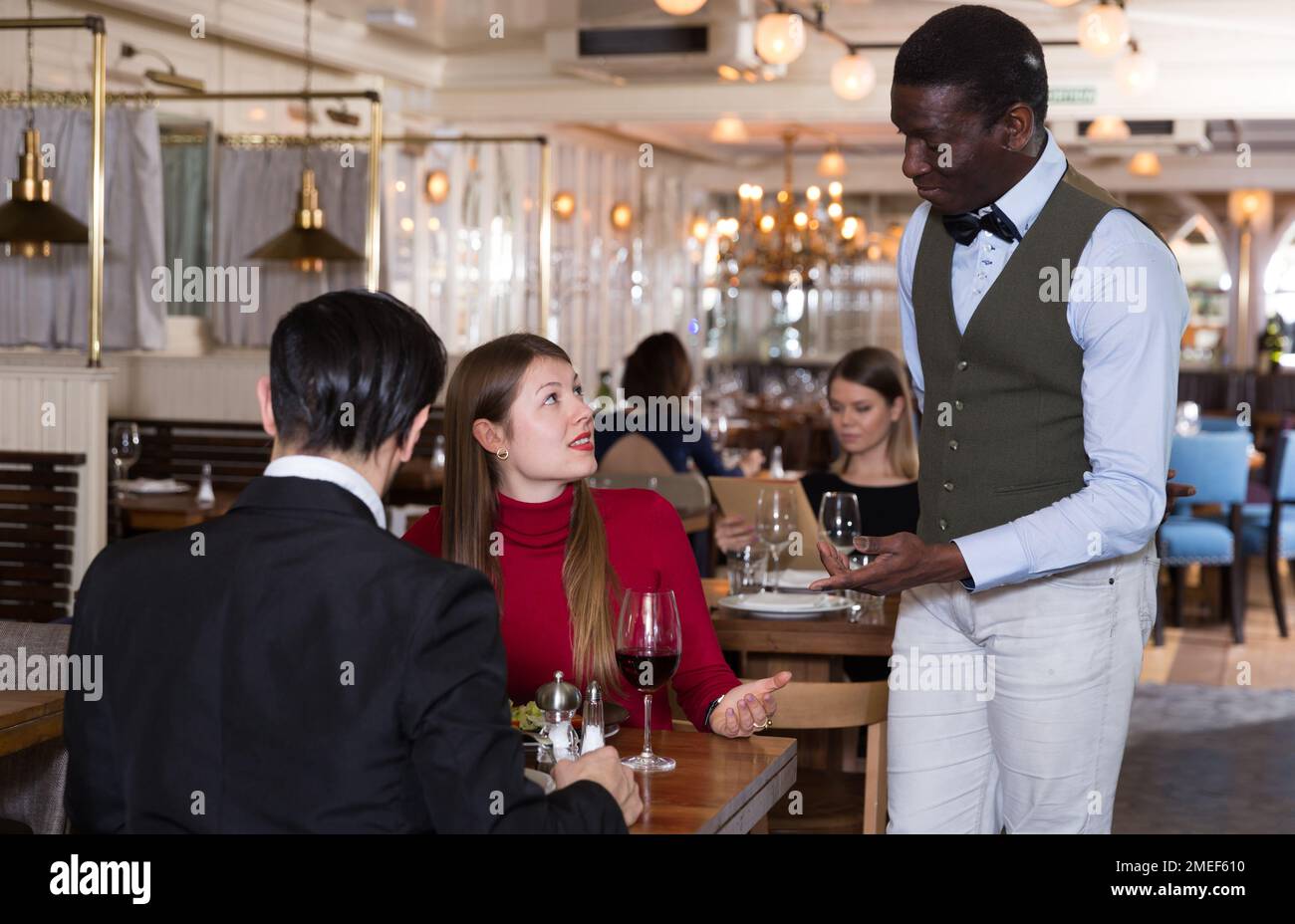 African American waiter talking with couple Stock Photo - Alamy