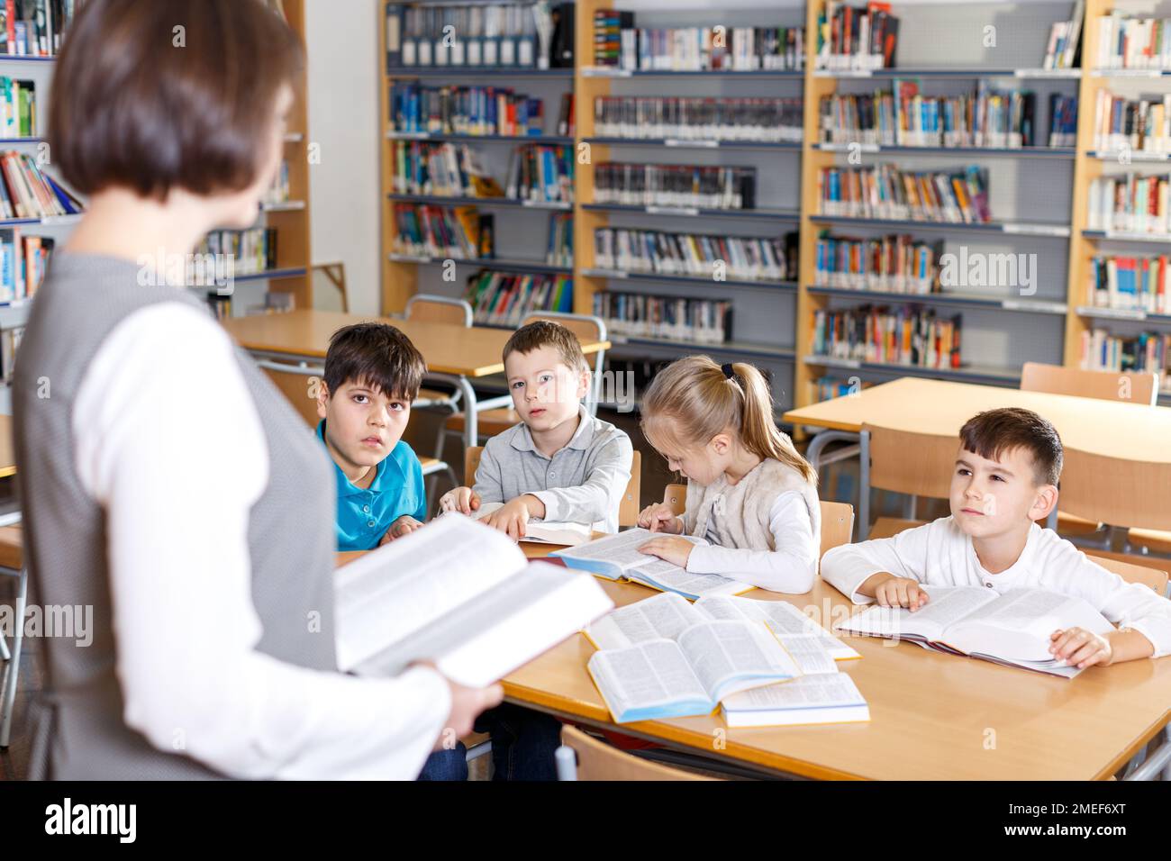 Female librarian and schoolkids during classes in library Stock Photo ...