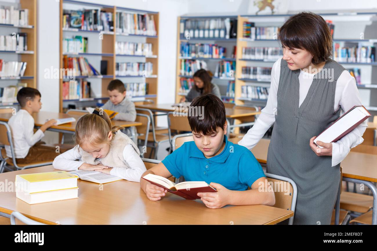 School kids studying with female teacher Stock Photo - Alamy