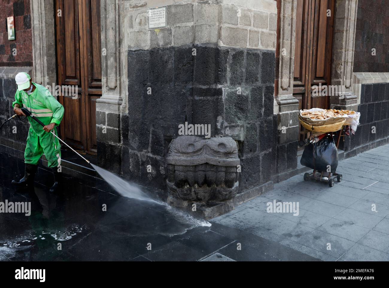 A city worker cleans the base of a building built on top of an ancient ...