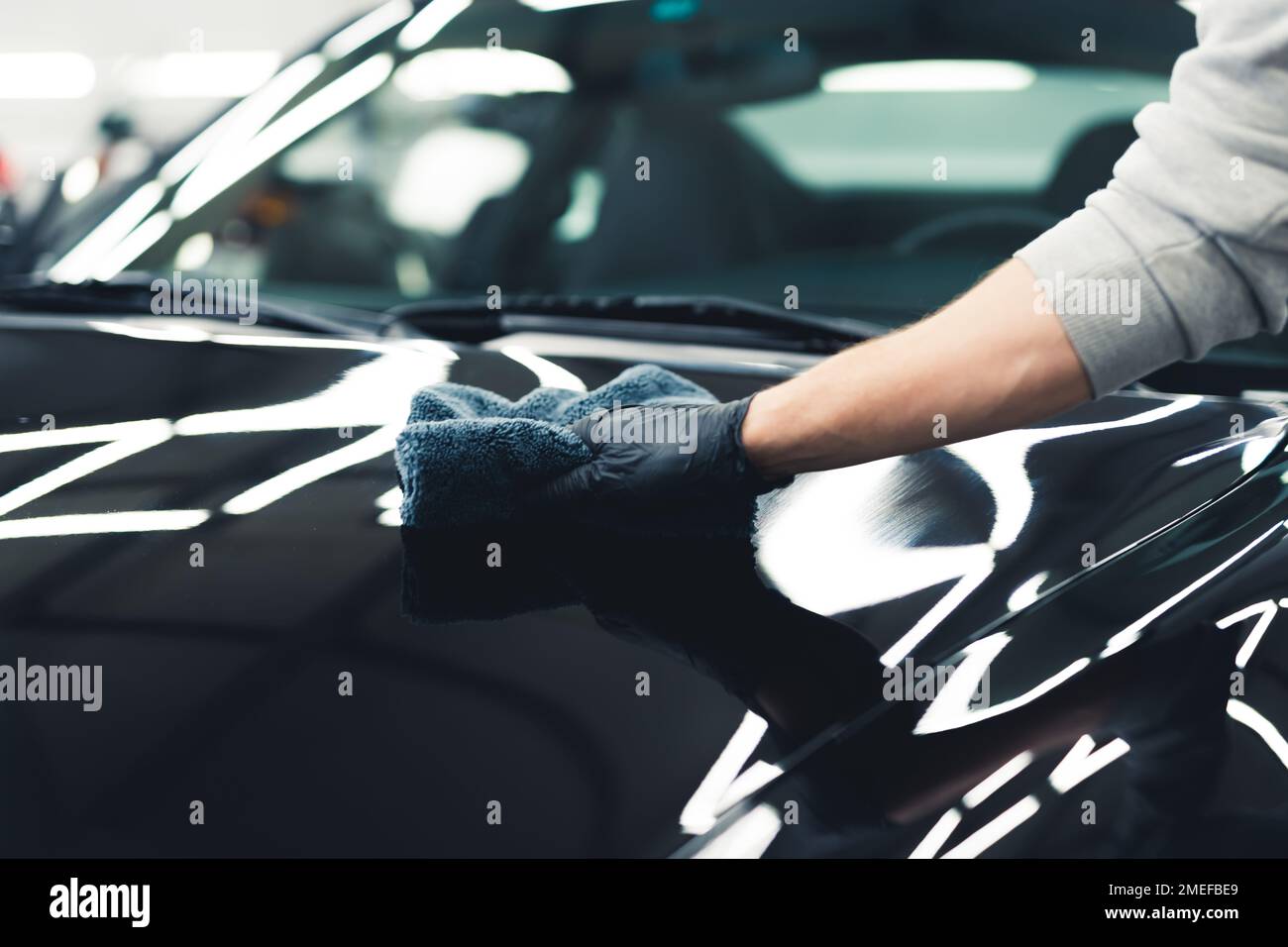 Unrecognisable man wearing black gloves applying ceramic coating to the ...