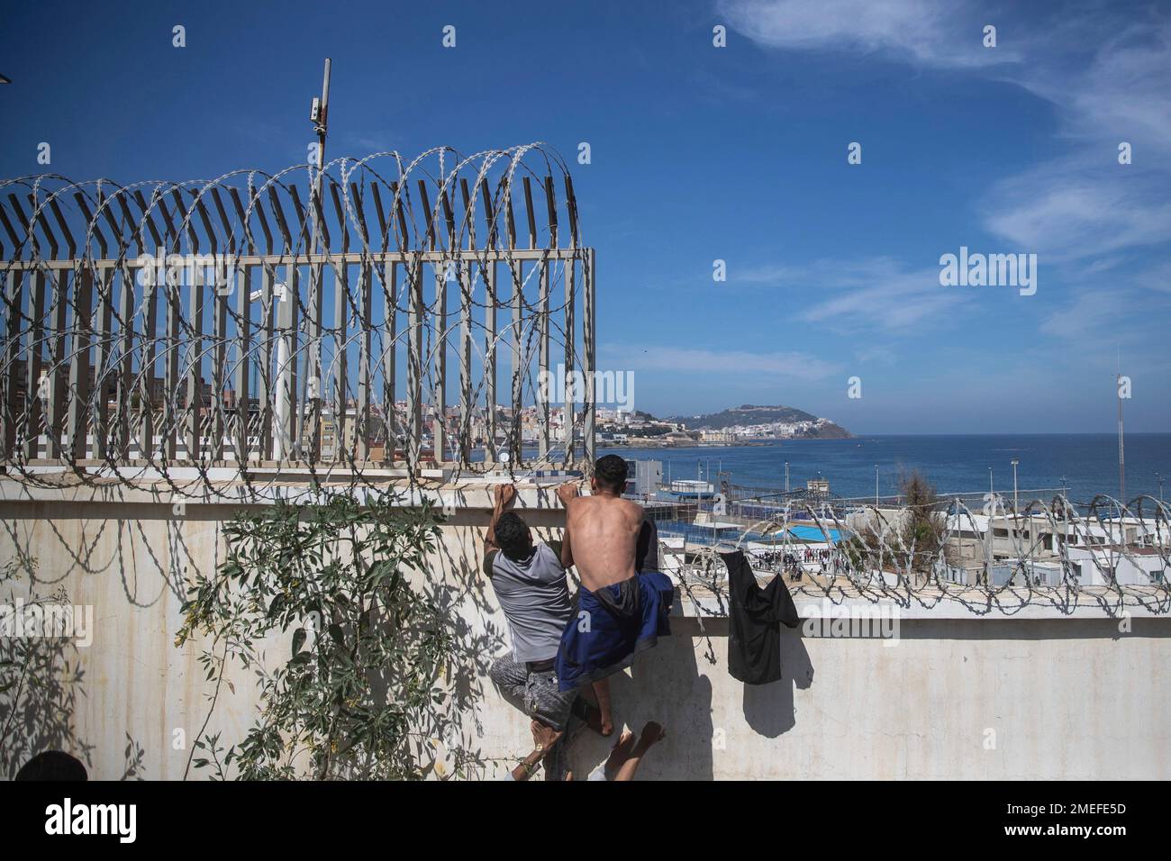 People climb a fence in the area at the border of Morocco and Spain ...