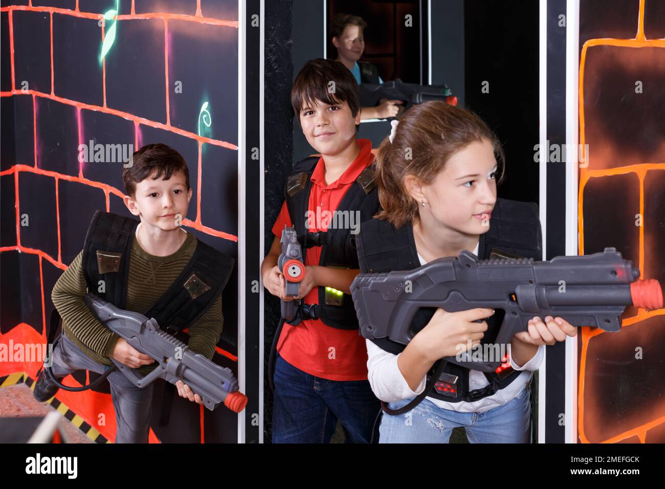 Laughing girl aiming laser gun at other players Stock Photo - Alamy