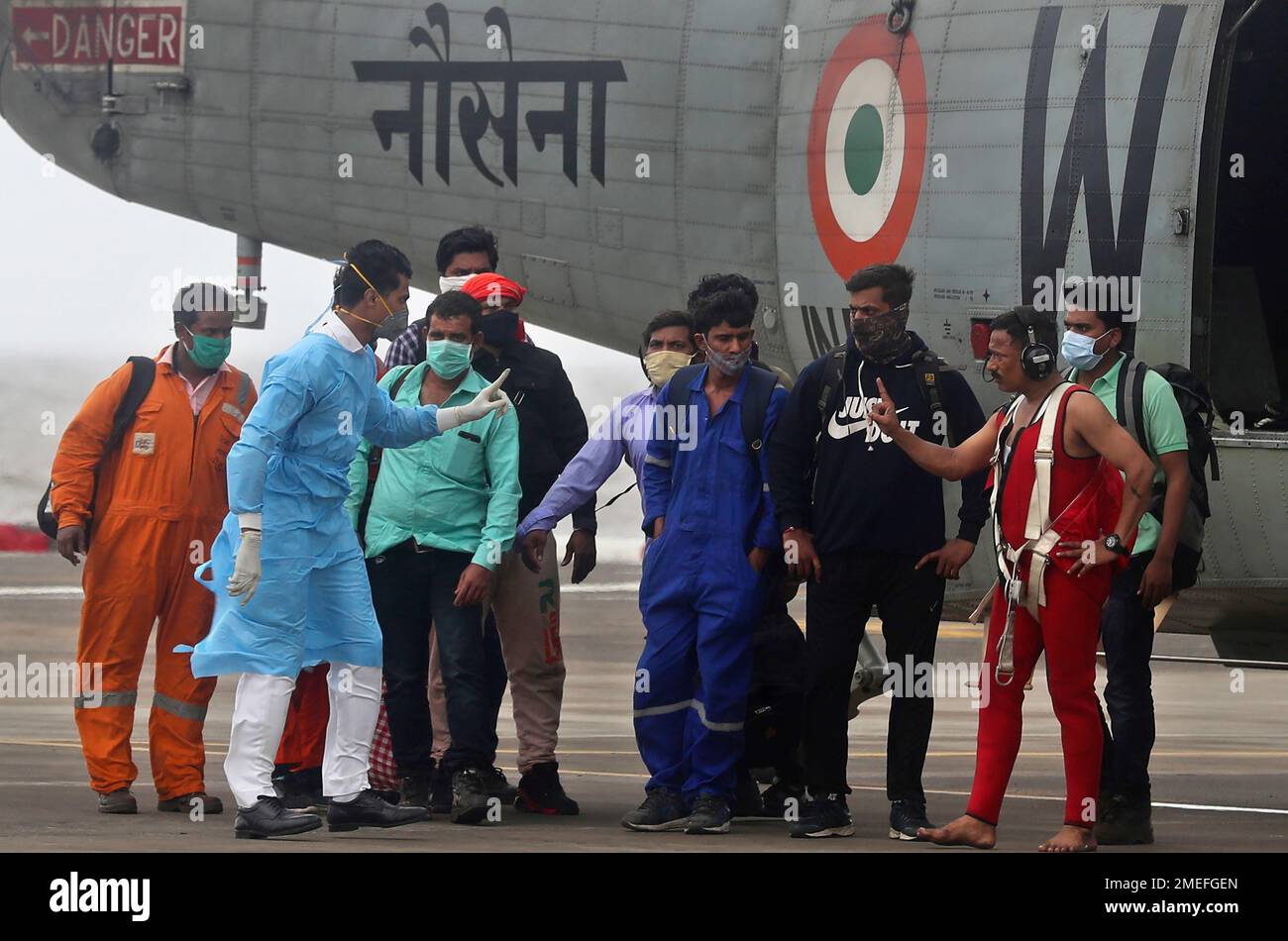 A paramedic, left, in protective suit interacts with a crew member ...