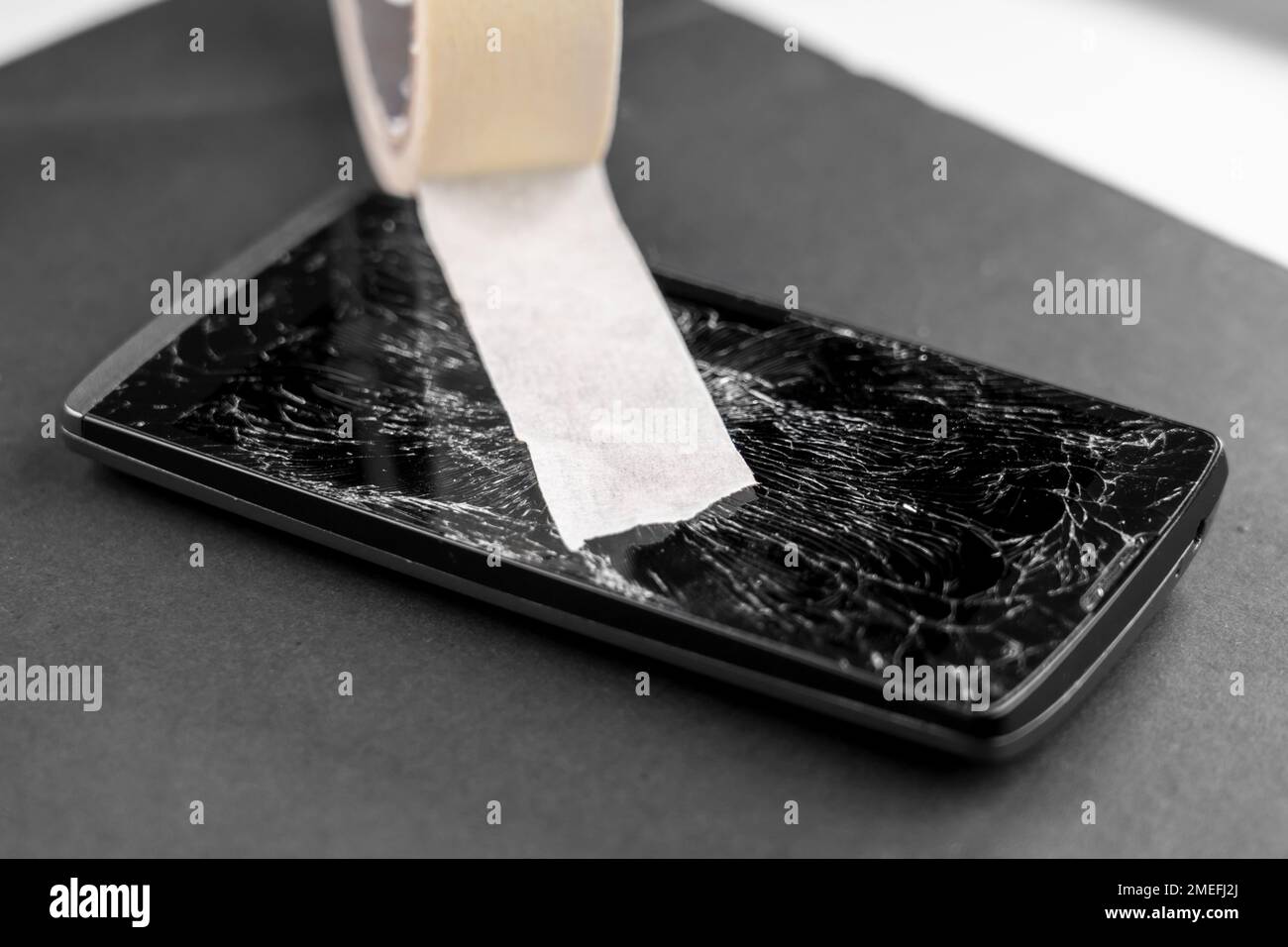 Broken cellphone with crushed screen glass and masking sticky paper ...