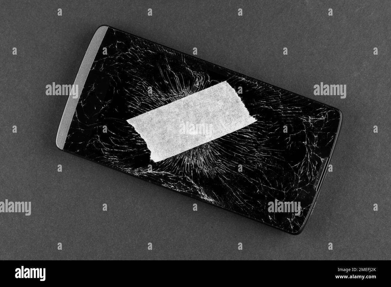 Broken mobile phone with shattered screen glass and masking piece of ...