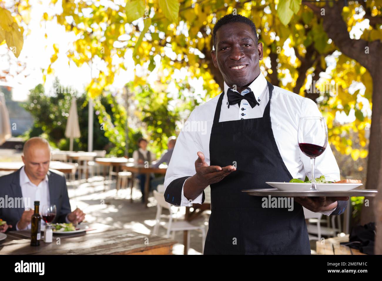 African American Waiter Who Is Standing With Order At Summer Cafe Stock