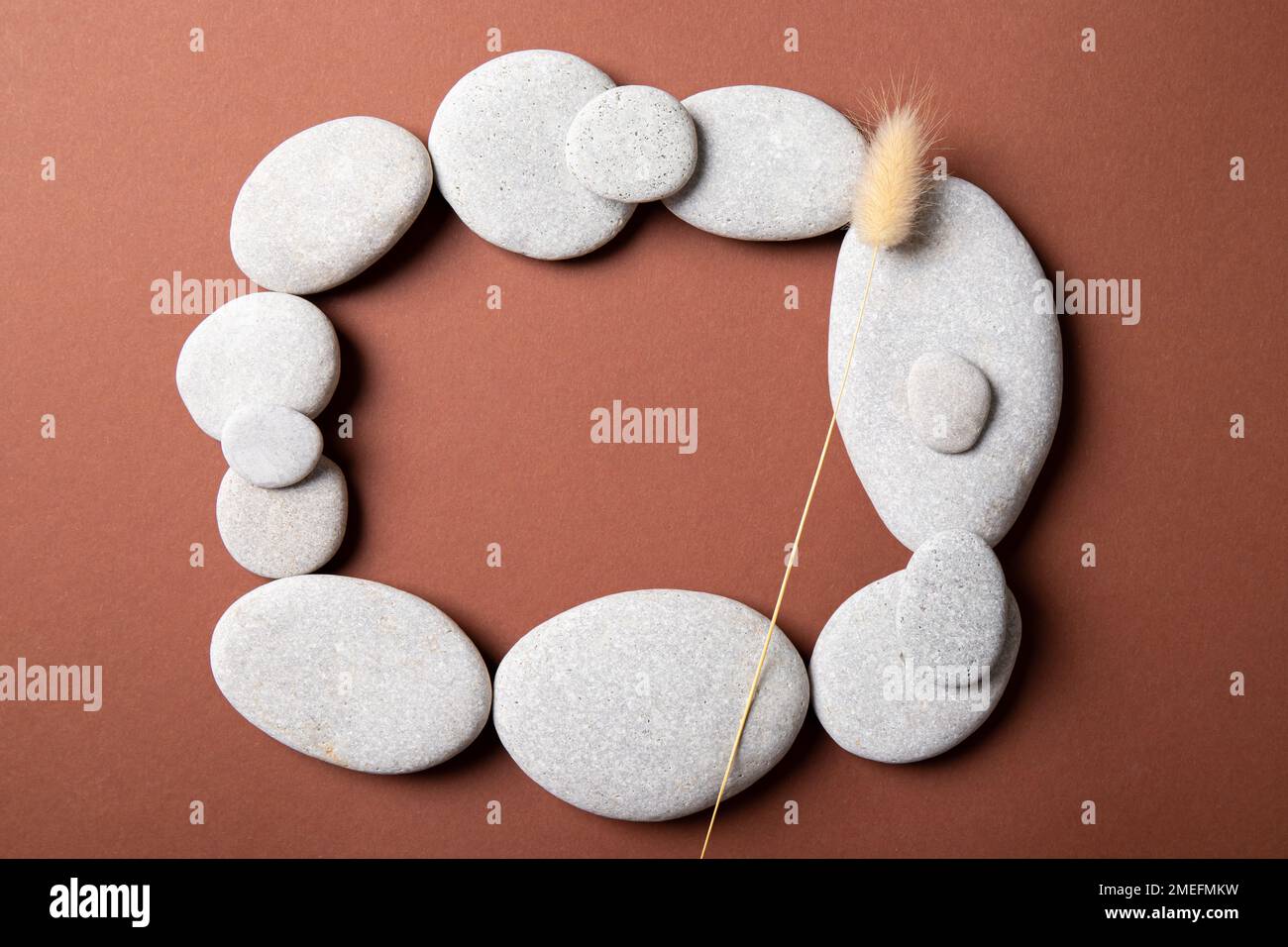 Flat lay view of frame made with flat smooth sea stones on empty brown ...