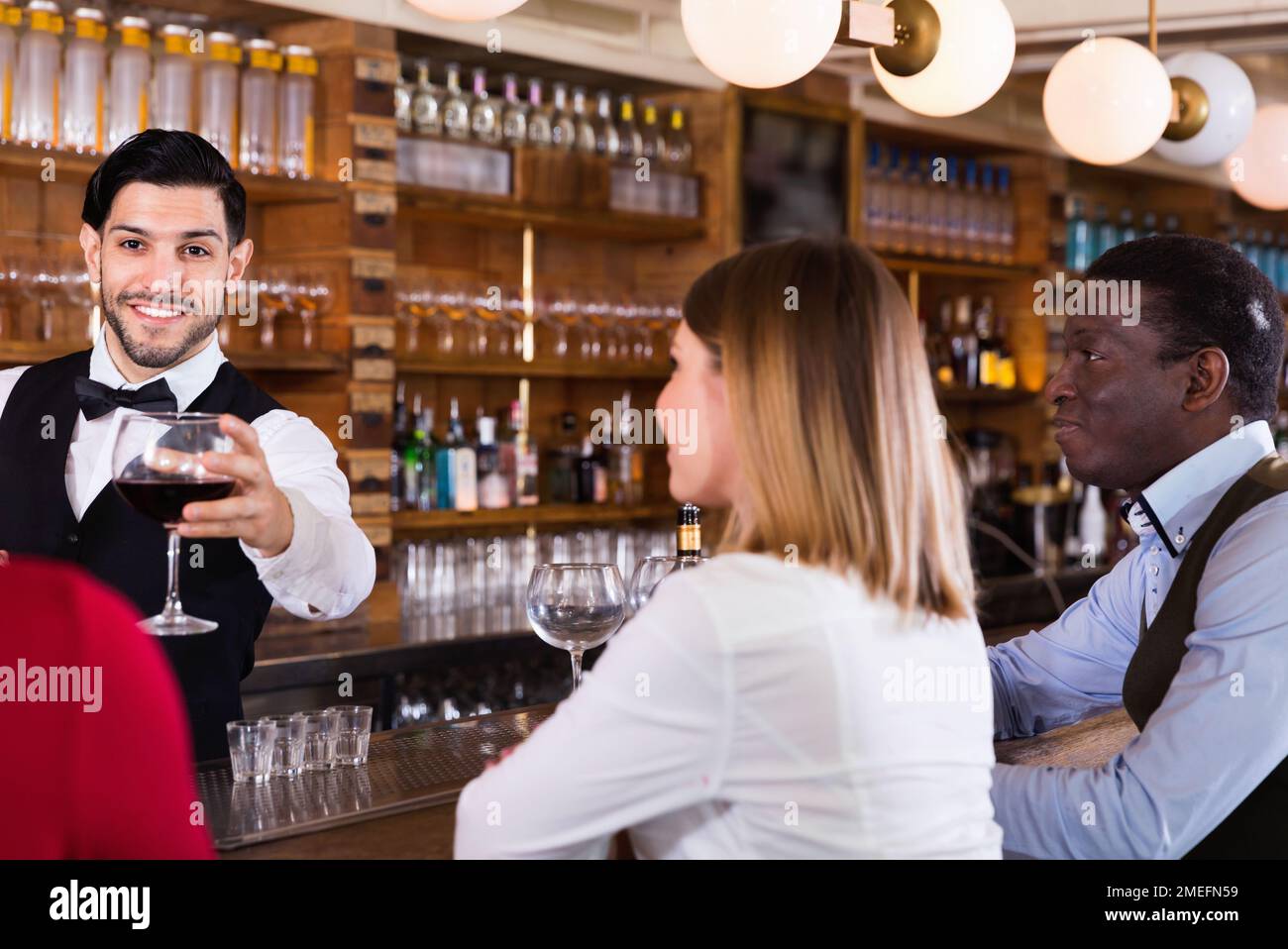 Portrait of barman and people who are standing near bar counter in ...