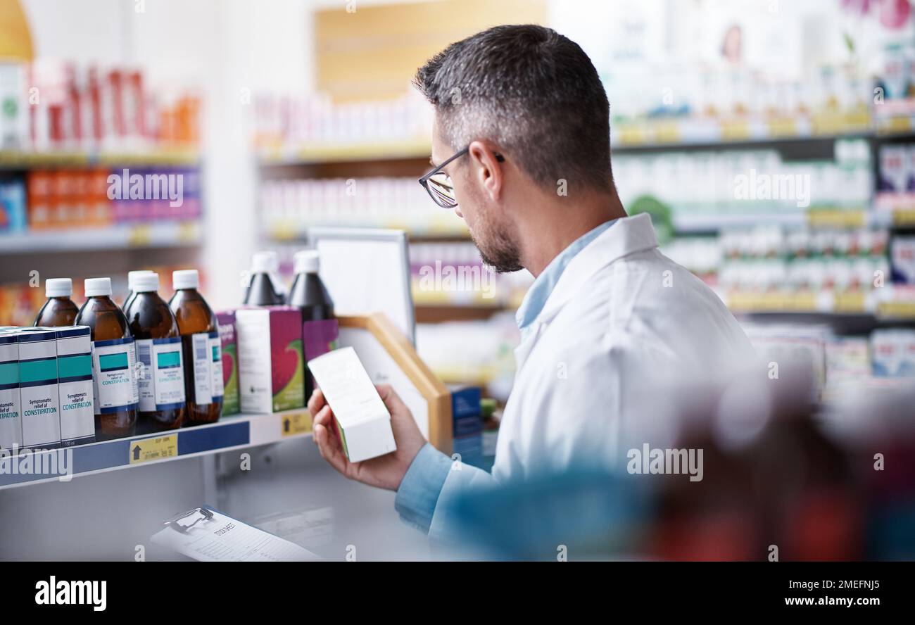 Running a well organized pharmacy. a mature pharmacist doing inventory ...