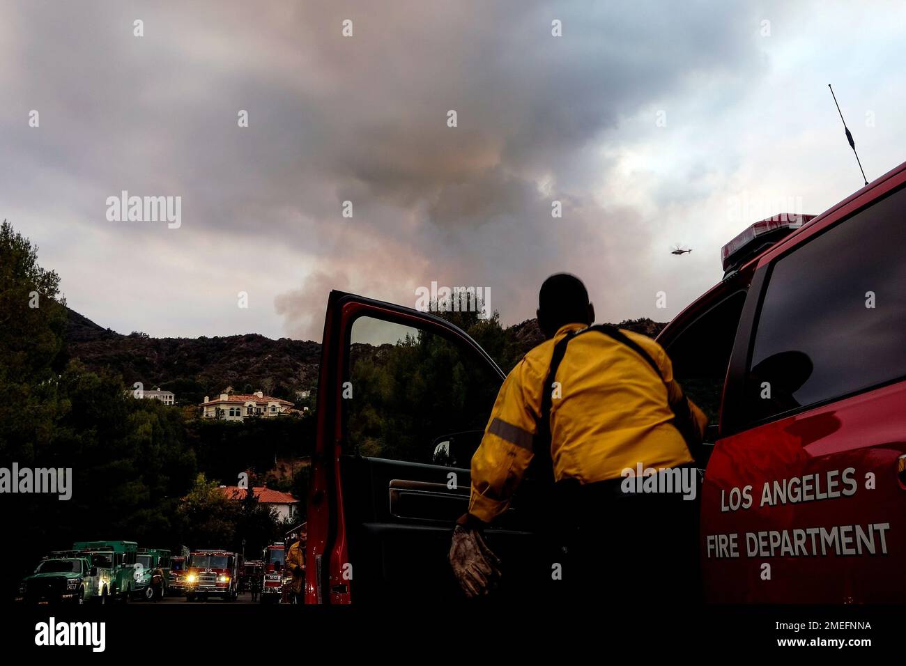 A Los Angeles Fire Department firefighter watches from his truck during ...